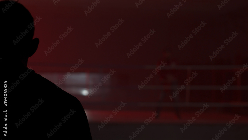 Silhouette of a man who comes into the room with a red light, back view ...