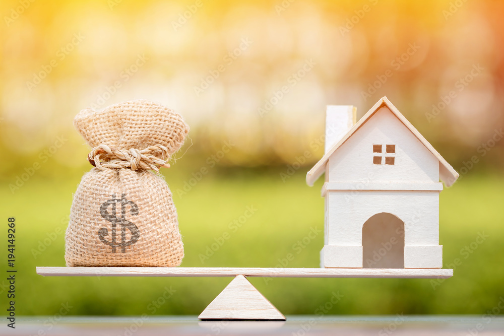 Home and money bag put on the scales with balance put on the wood in ...