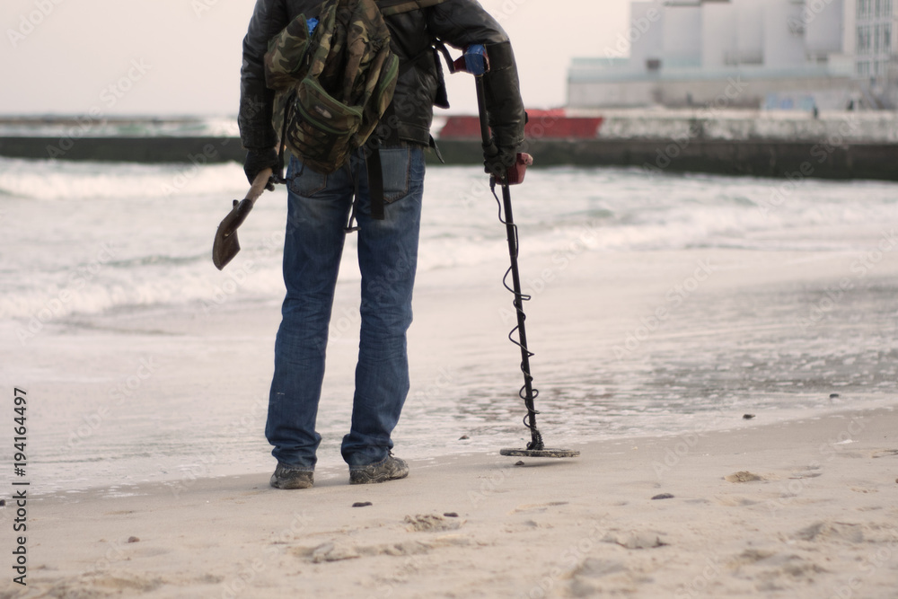 Man with metal detector on the beach looking for lost objects under the ...