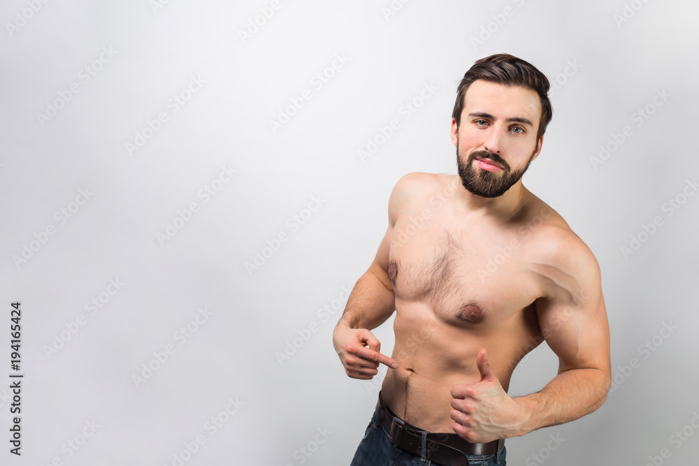 Good-looking and awesome guy is standing of a wall and pointing on ...