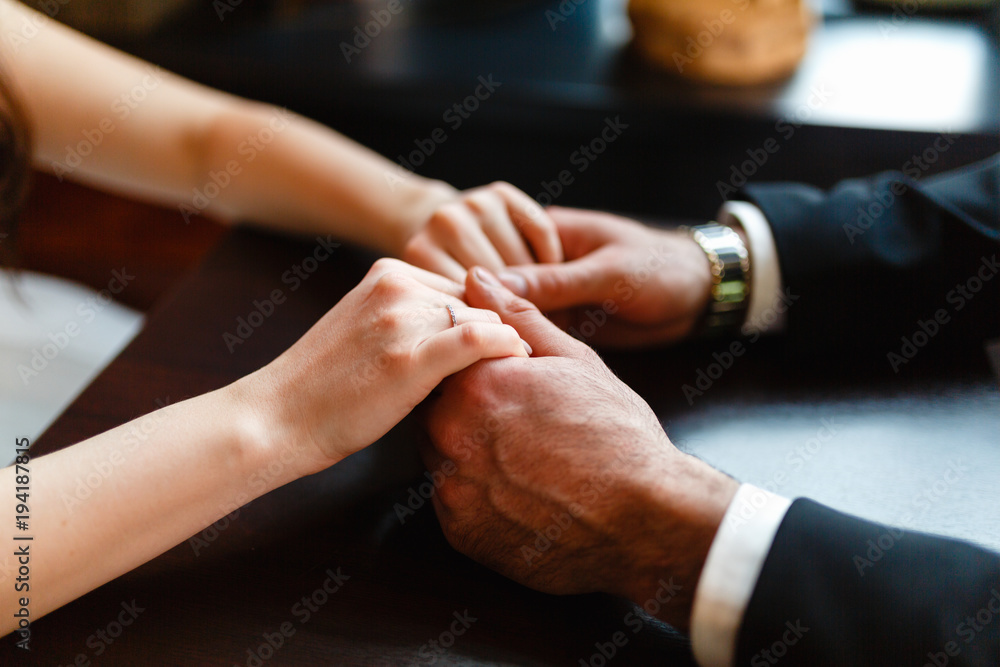 Young Couple Holding Hands On The Table Opposite Each Other Close Up