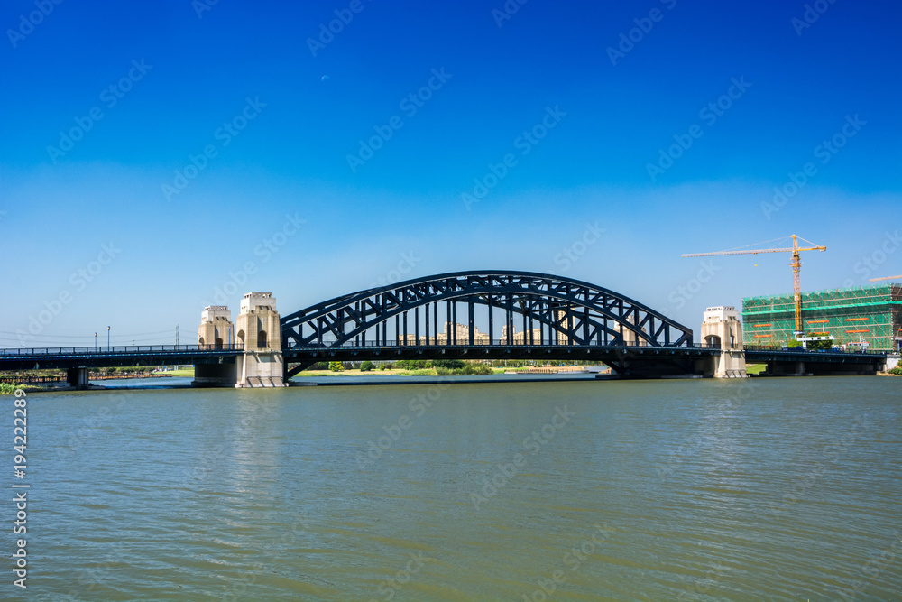 Wooden boat passing the historic Howrah bridge in silhouette at sunrise ...