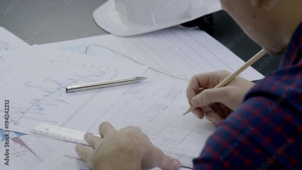 Vidéo Stock Engineer builder at his desk performs a pencil drawing on ...