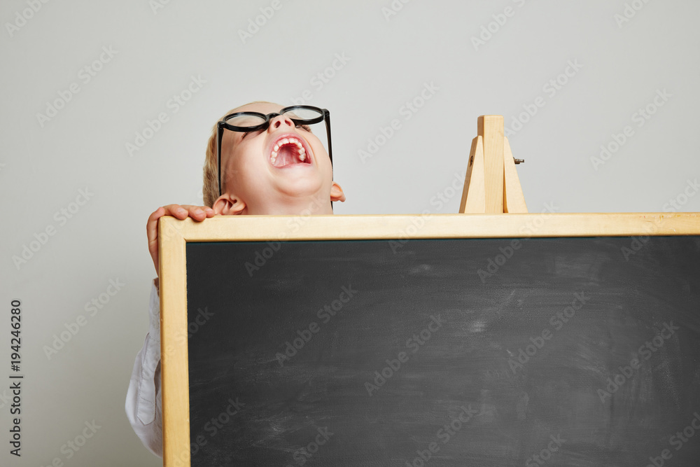 Lachendes Kind steht hinter einer Tafel Stock Photo | Adobe Stock