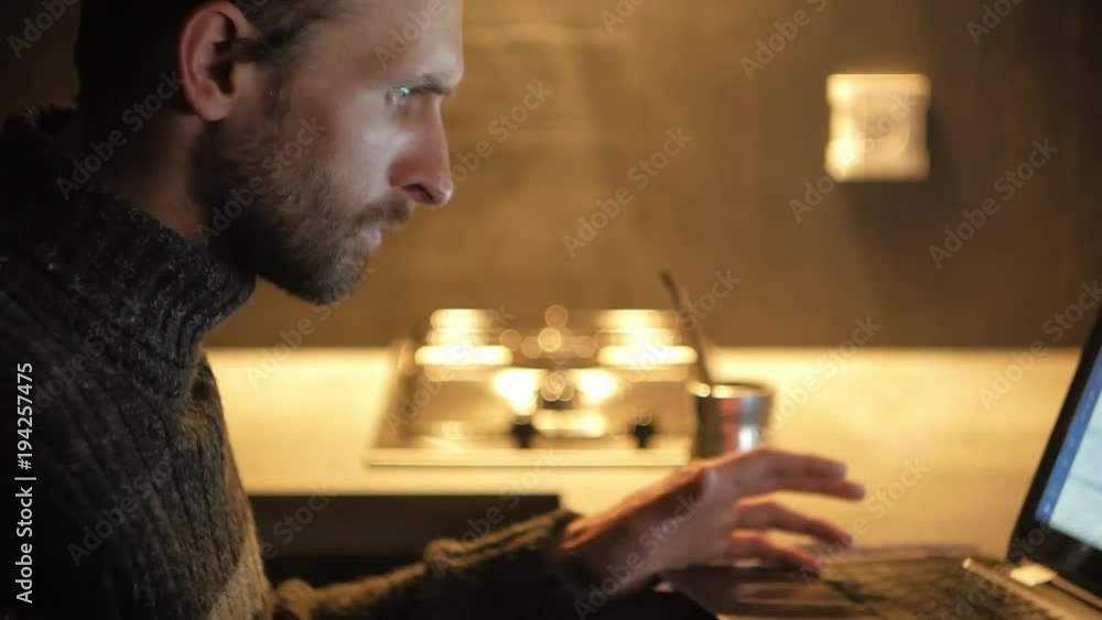 Bearded man works at home on computer or laptop and tries find the ...