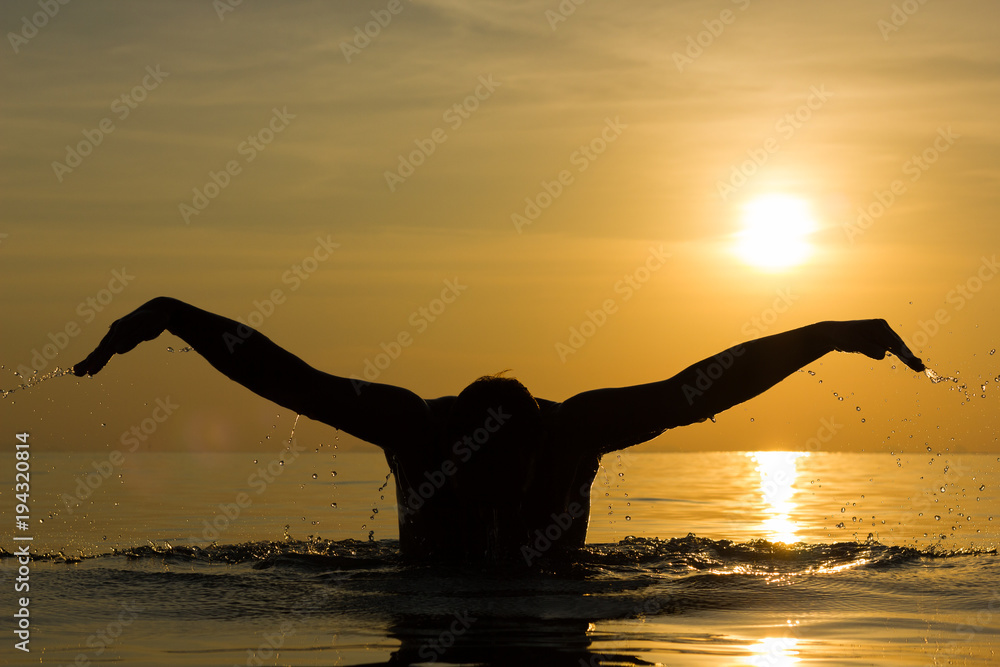 Silhouette of man with open arms swimming butterfly stroke technique ...