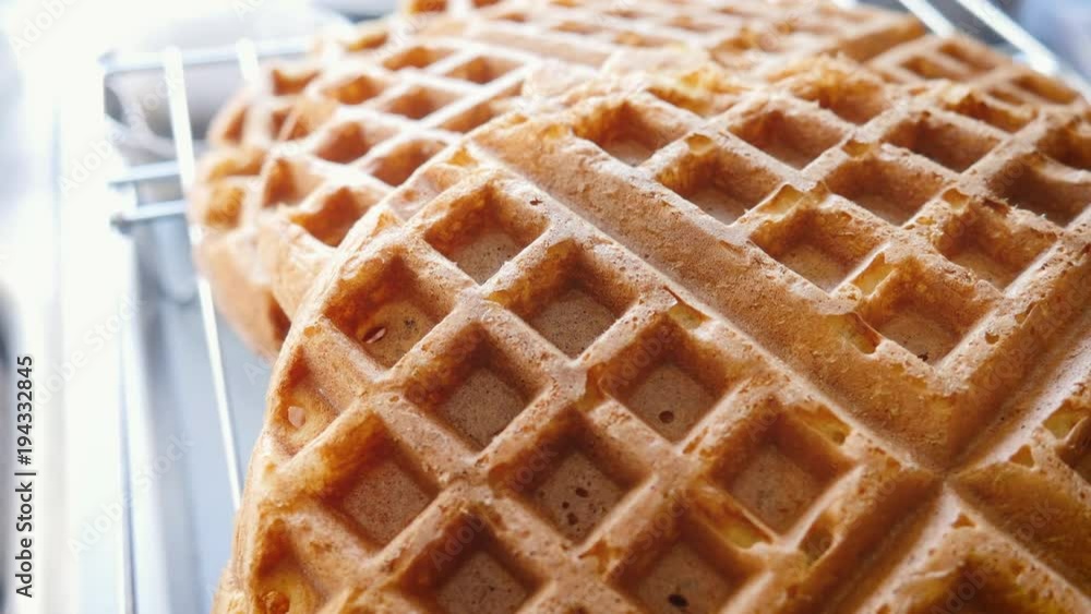 Woman lifts a waffle from a stack of golden brown treats in 4k. The ...