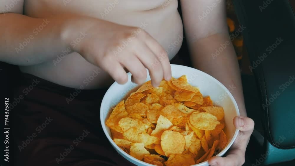Thick boy boy eating potato chips. Folds of fat on abdomen of the child ...