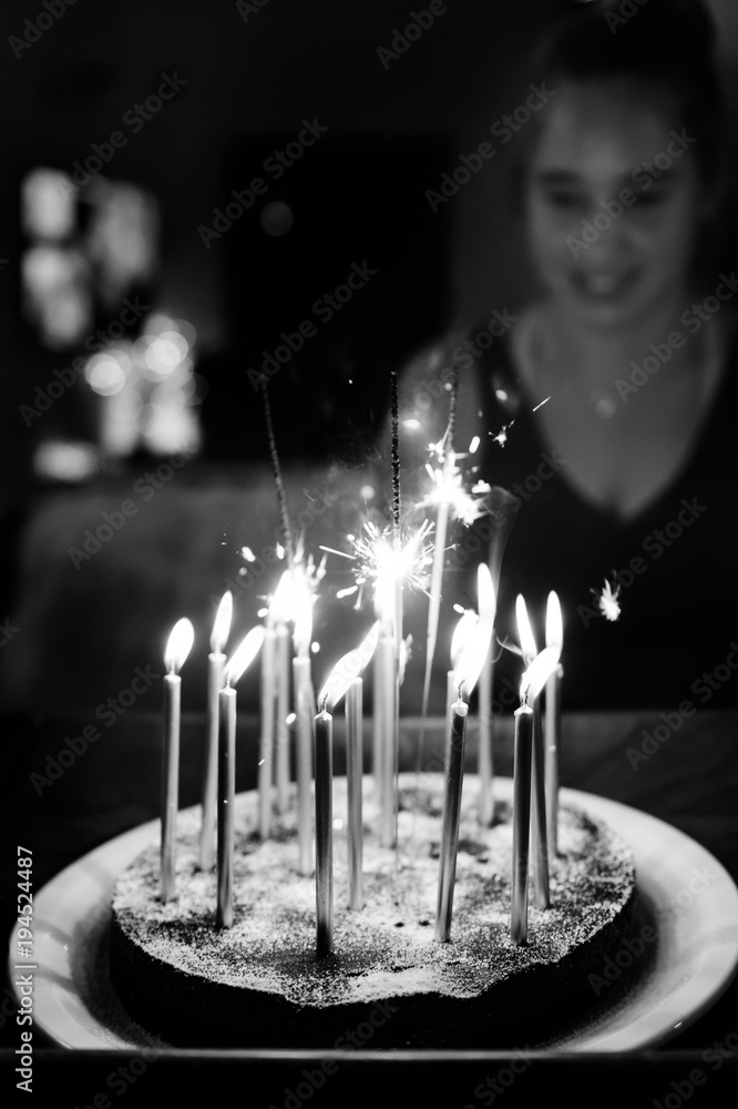 Teenage girl with a candle lit birthday cake Stock Photo | Adobe Stock