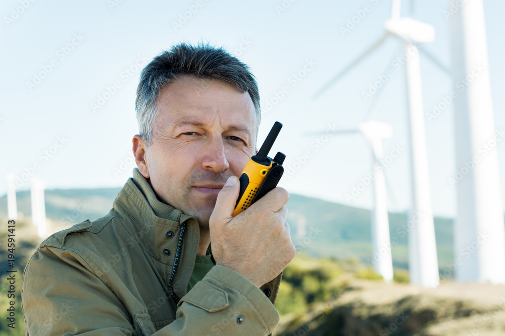 Man talking with portable radio transmitter outdoor over the wind ...
