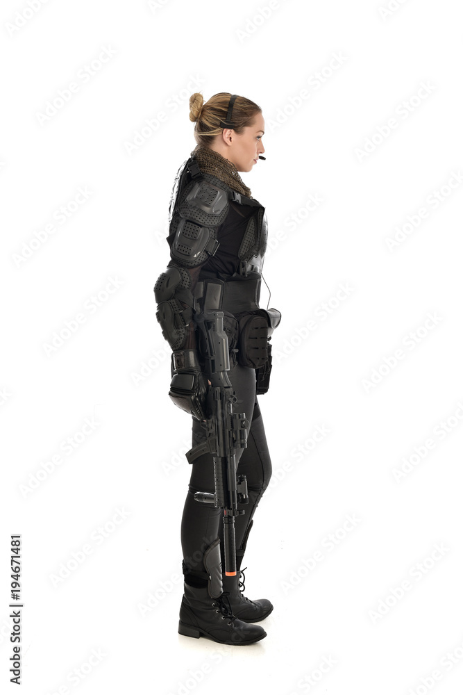 full length portrait of female soldier wearing black tactical armour ...