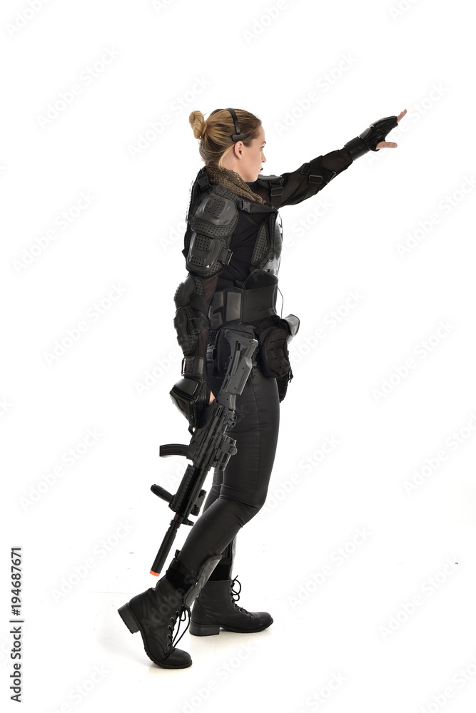 full length portrait of female soldier wearing black tactical armour ...