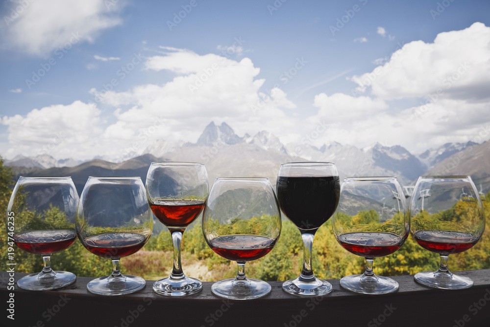 Five glasses of cognac and two glass of red and rose wine stand against ...