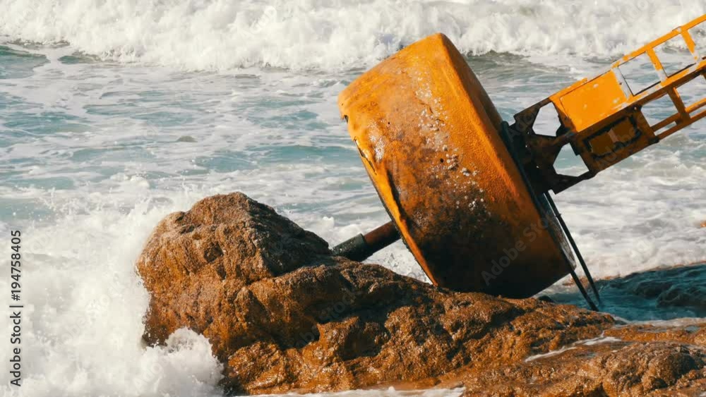 Large yellow buoy on the shores of azure sea. The waves hit the buoy ...
