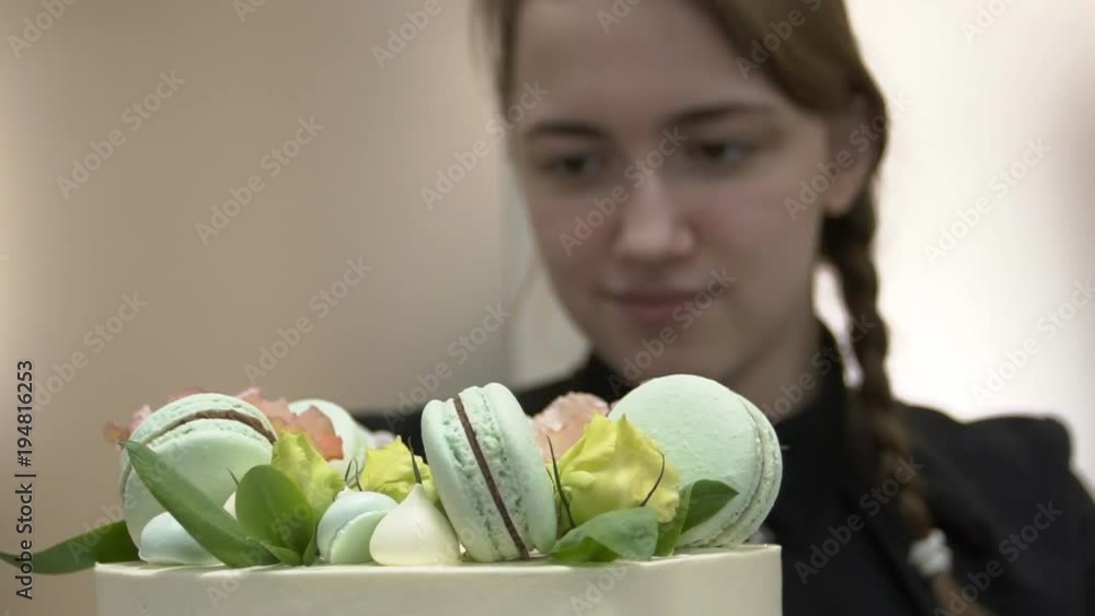 Woman chef is decorating delicious cake in kitchen in restaurant. Young ...