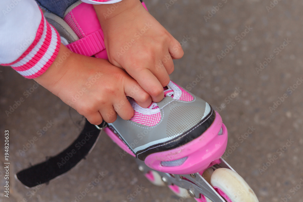 Little girl sitting on parapet and putting on rollers in the park Stock ...