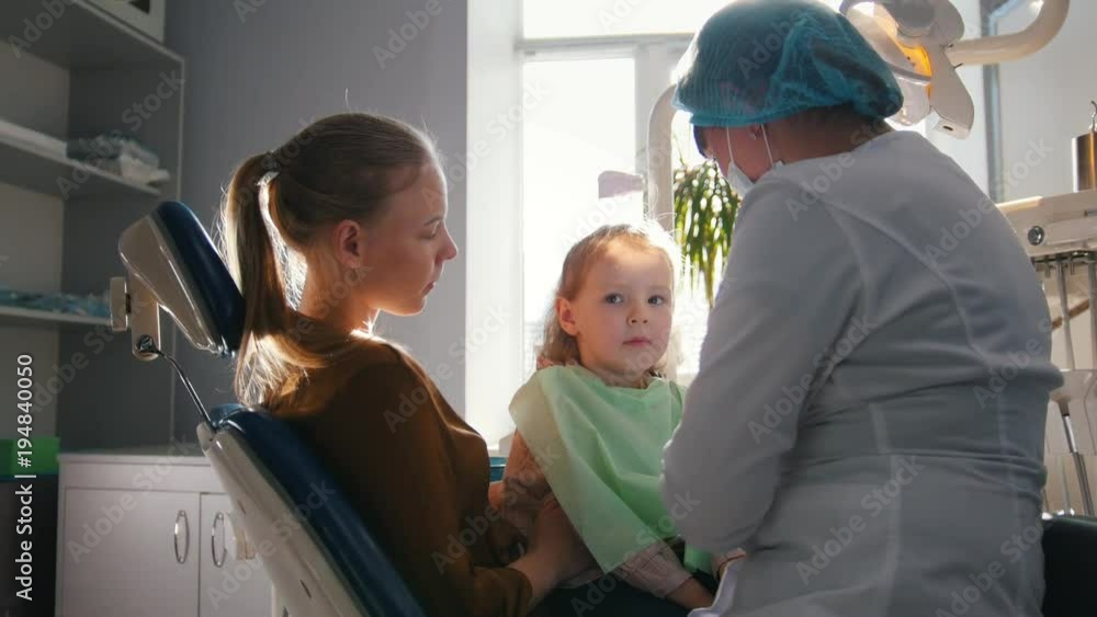 Dentist examining a little girl sitting on her mom's lap vídeo do Stock ...