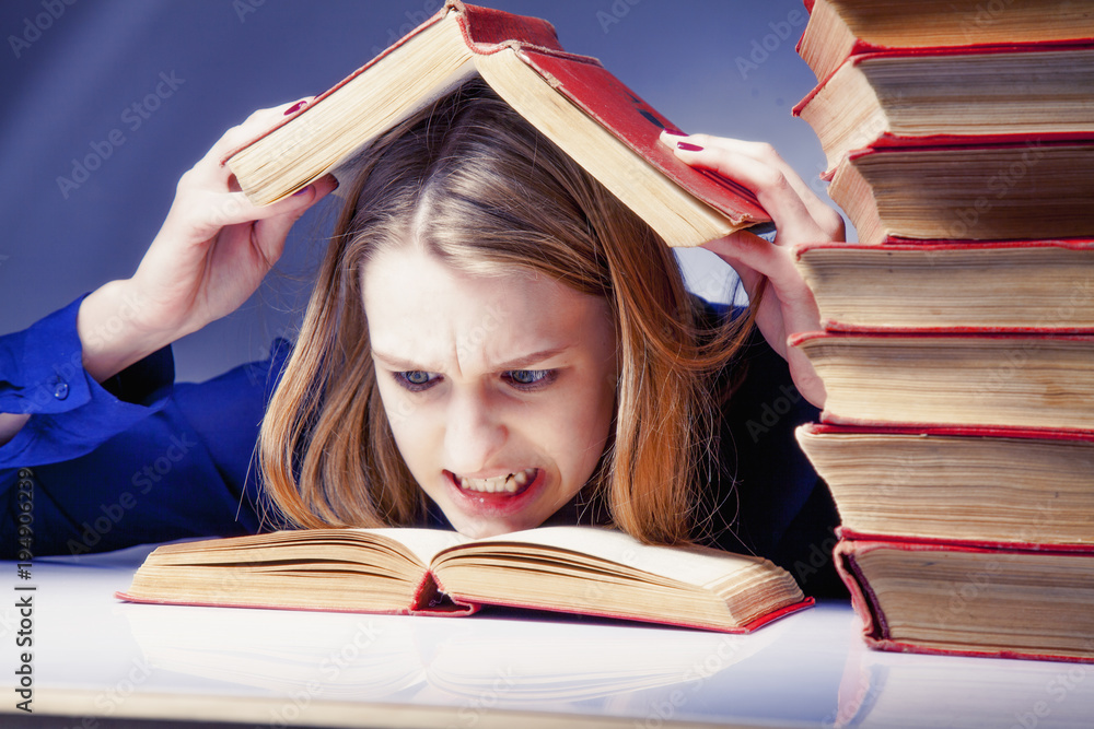 Young frustrated female student with books as symbol of heavy and ...