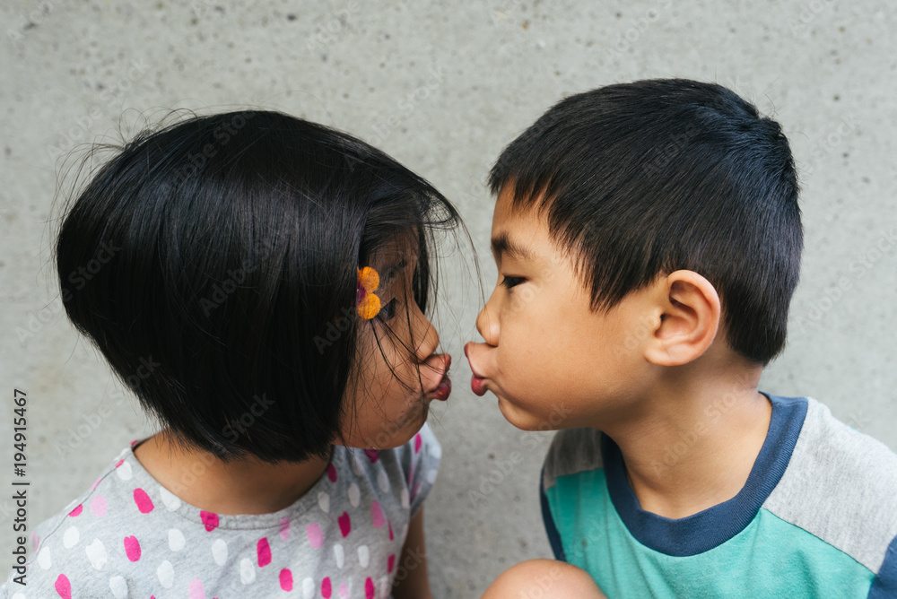 Asian American toddlers getting ready to kiss each other with puckered ...