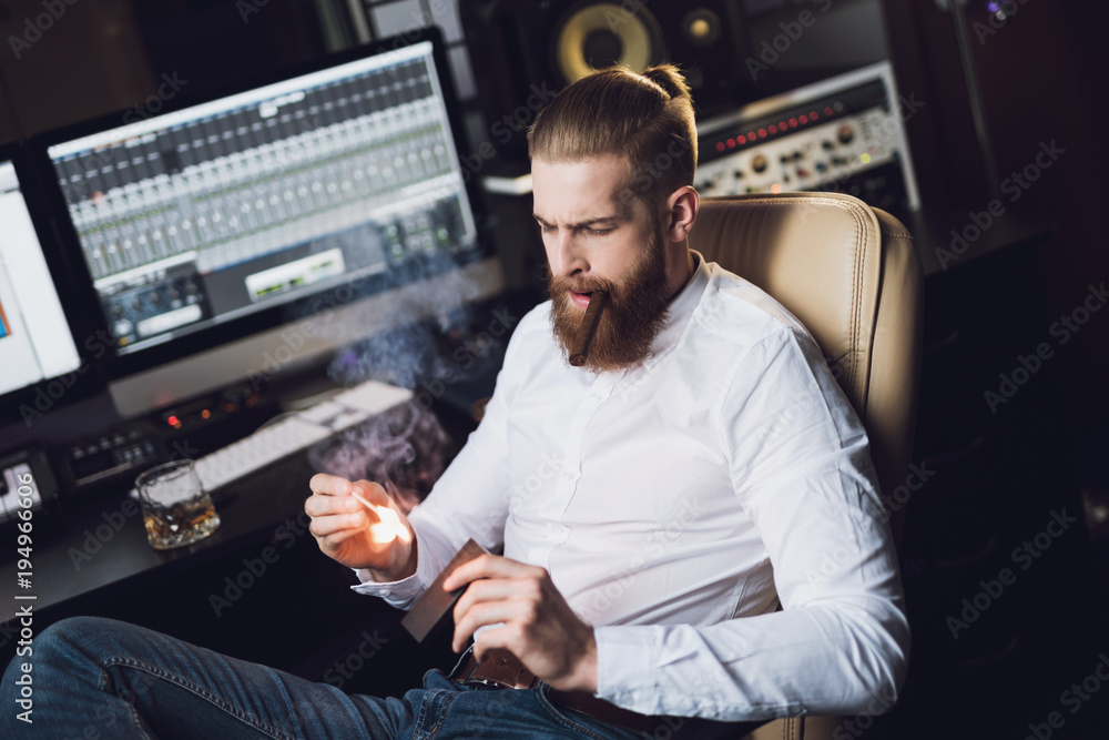 The male producer sits in the recording studio behind the remote ...