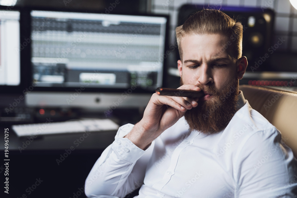The male producer sits in the recording studio behind the remote ...