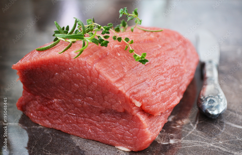 Red meat. Raw beef tenderloin on a kitchen counter with rosemary and ...