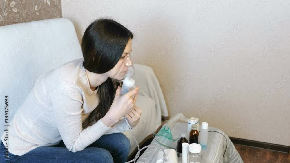 Use nebulizer and inhaler for the treatment. Young woman inhaling ...