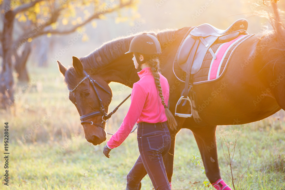 Young rider girl walking with horse in park. Equestrian recreation ...