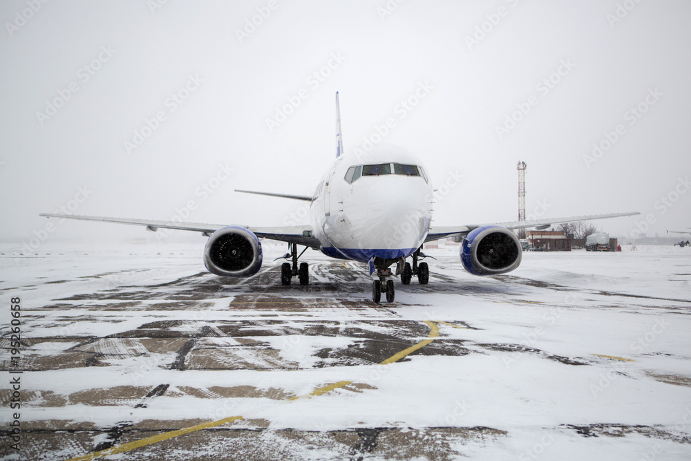 Airliner on runway in blizzard. Aircraft during taxiing at heavy snow ...