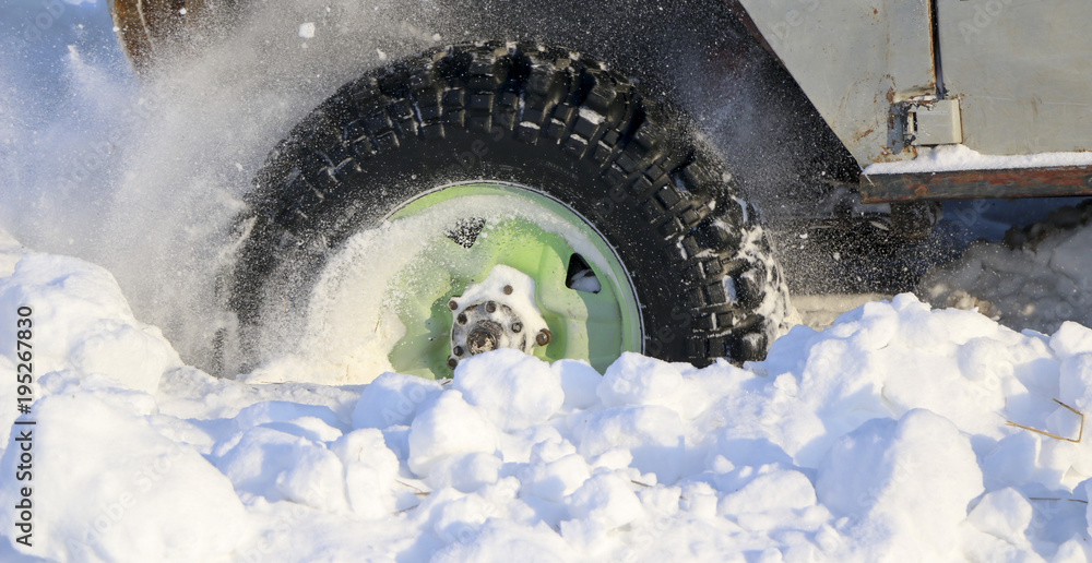 the wheel of the car is stuck in the snow. spray of snow from the ...