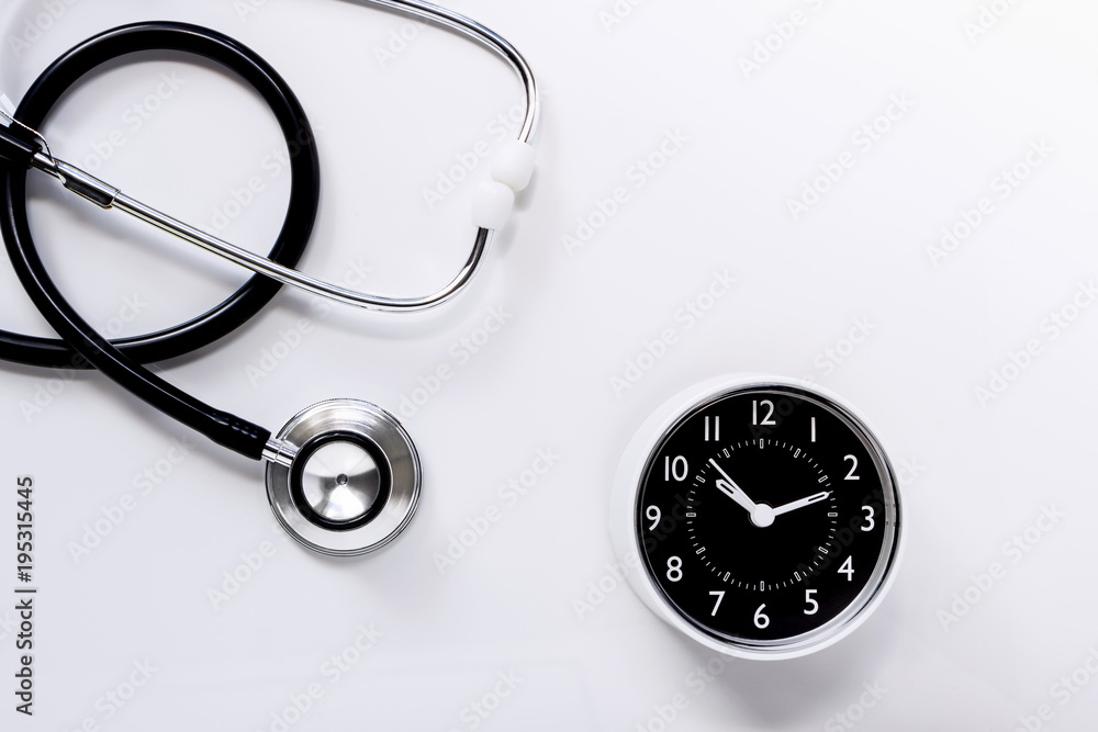 Stethoscope with a clock on white table background. The stethoscope is ...