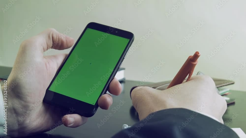 Hands of businessman working in office at with mobile green screen. One ...