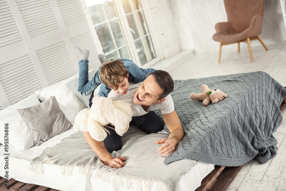 Our day off. Attractive inspired dark-haired daddy laughing and lying ...