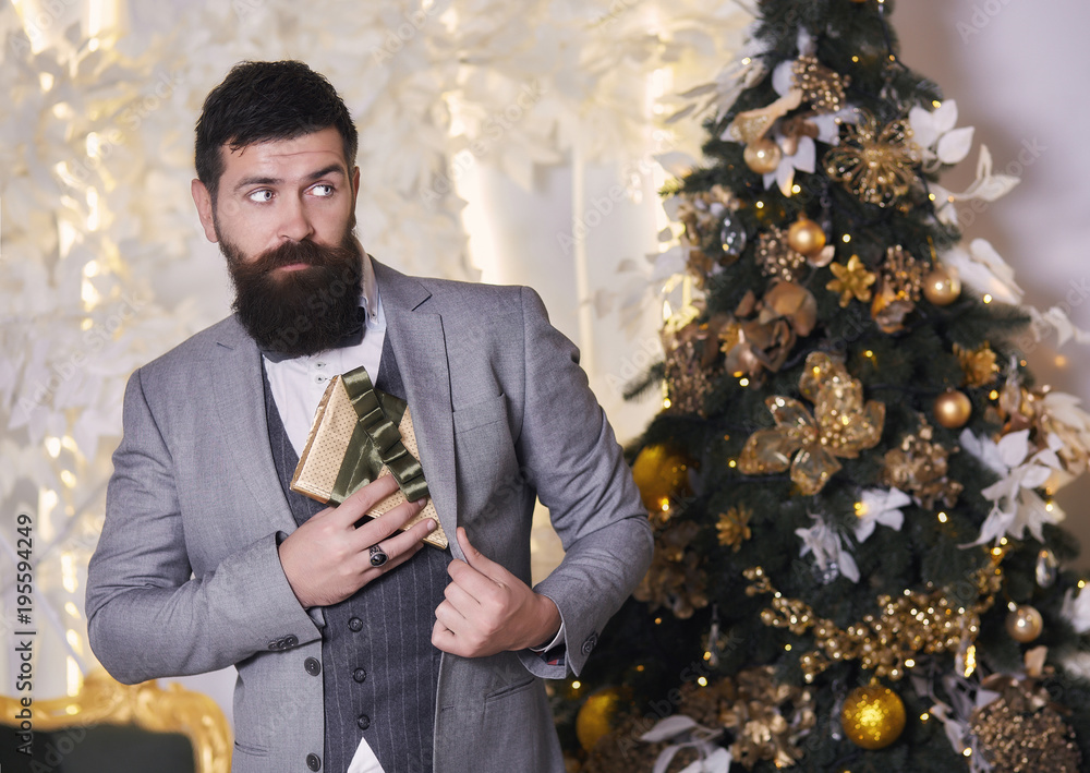 A man in an elegant suit hides a gift hidden under his jacket. Handsome ...