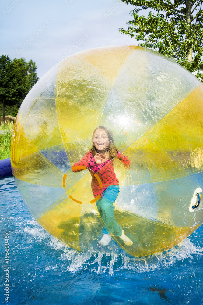 Young girl running inside a floating water walking ball. Stock Photo ...