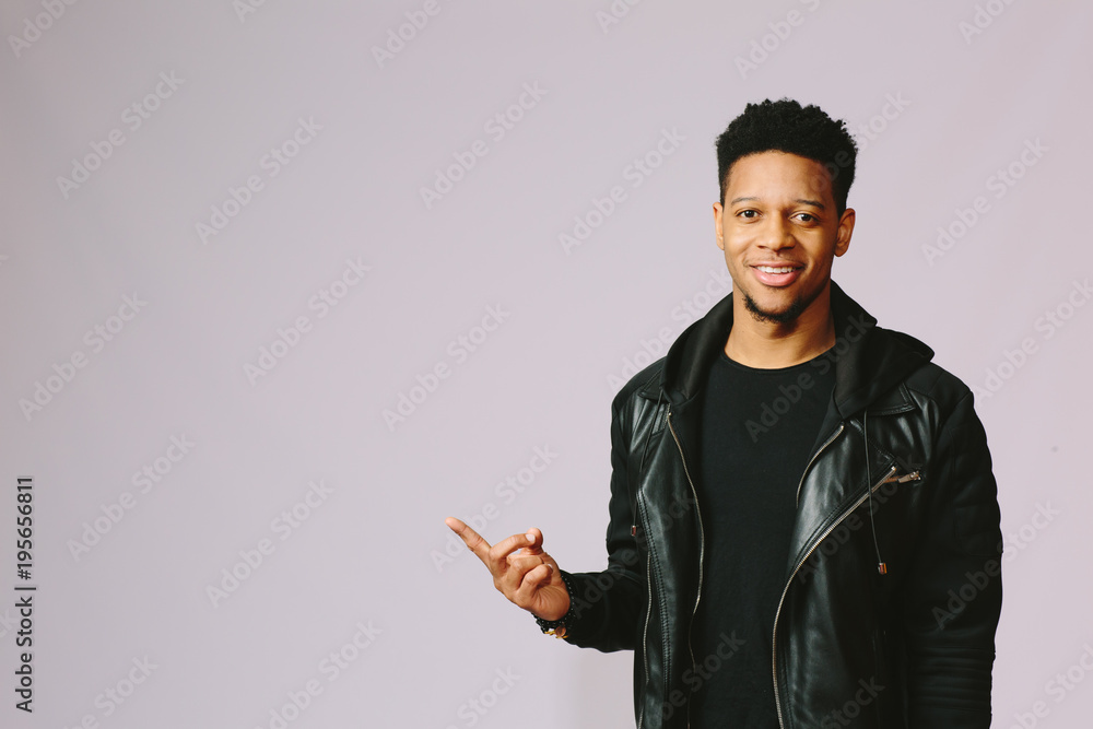 cool guy smiling at the camera and pointing up isolated on a grey ...
