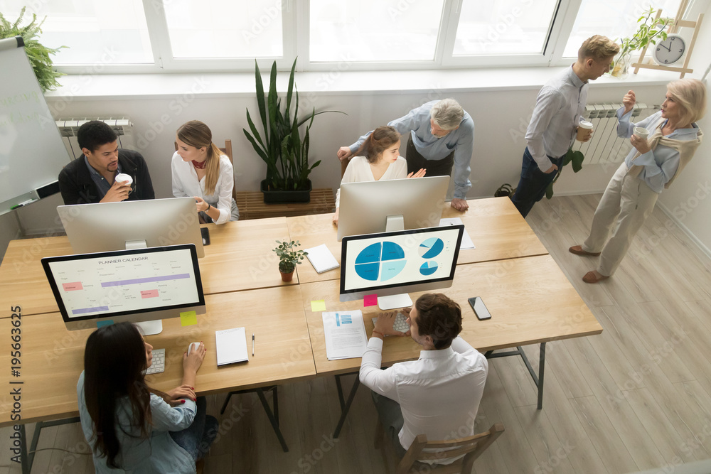 Diverse young and senior office workers collaborating and talking ...