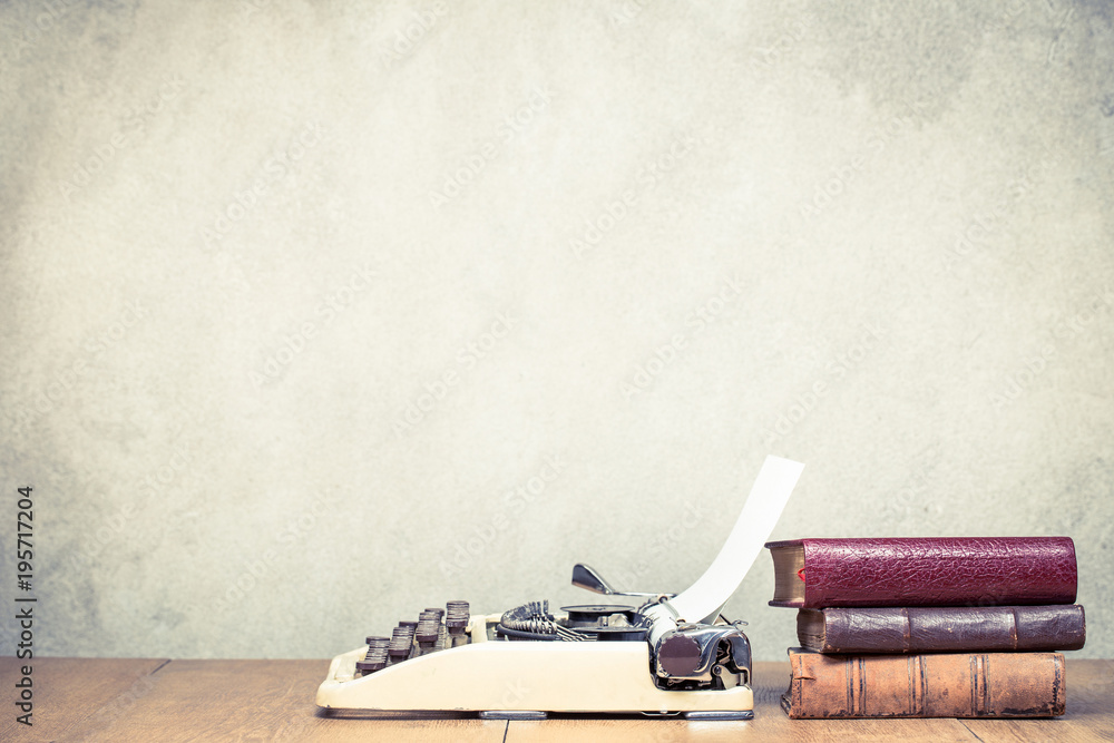 Retro typewriter with sheet of paper and old books on wooden table ...