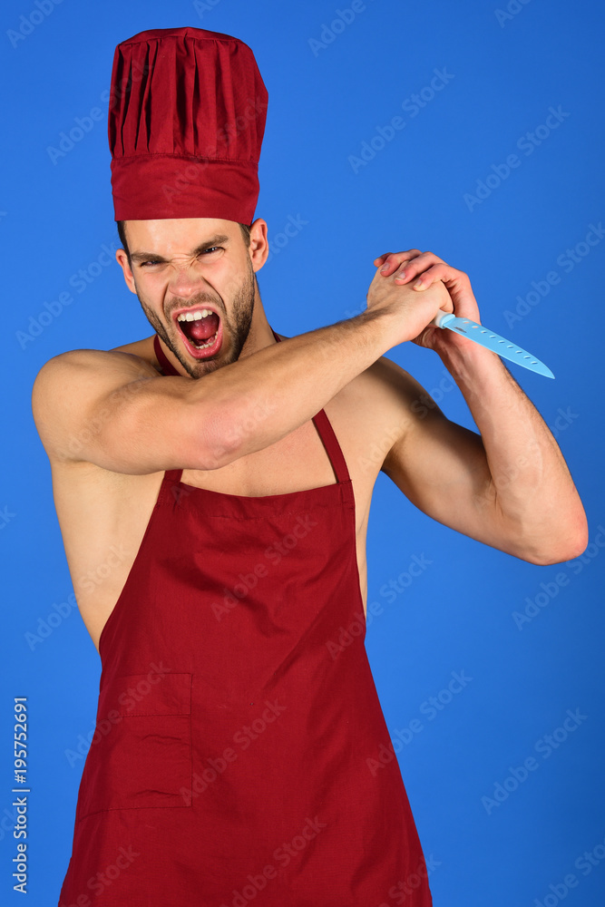 Angry young chef holding knife. Chef pretends to throw blue knife ...