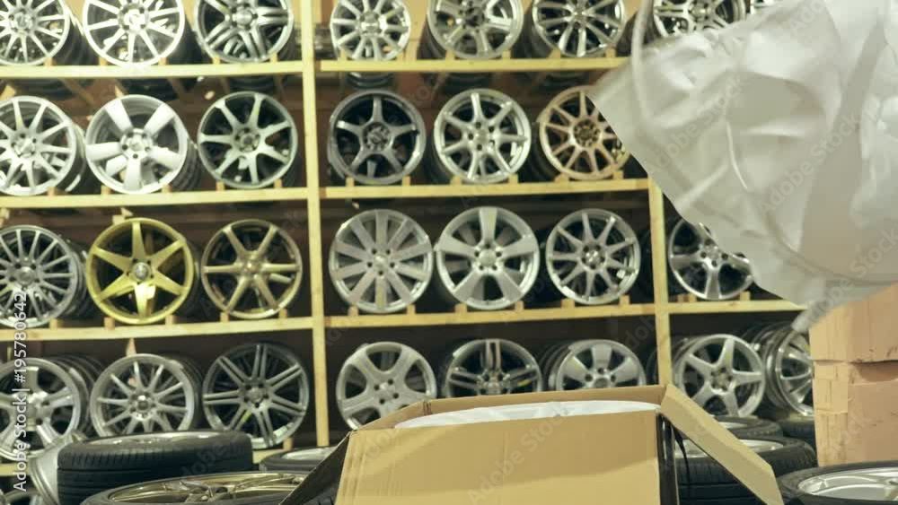 The man buys alloy wheels in his shop for his car. A man packs a disc ...