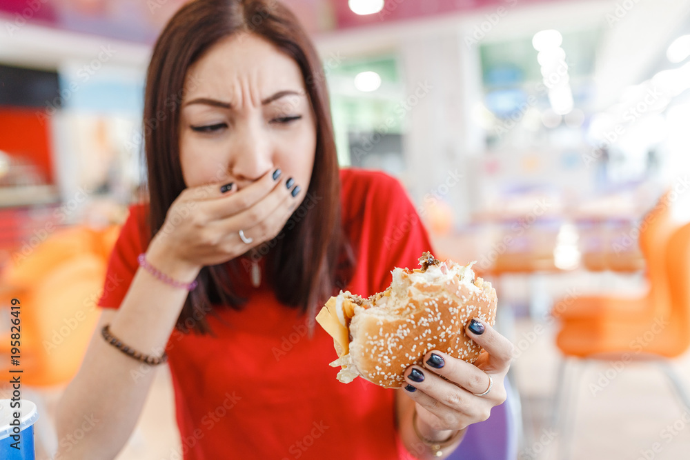 Woman with burger in hand, making bad and disgusting face, concept of ...