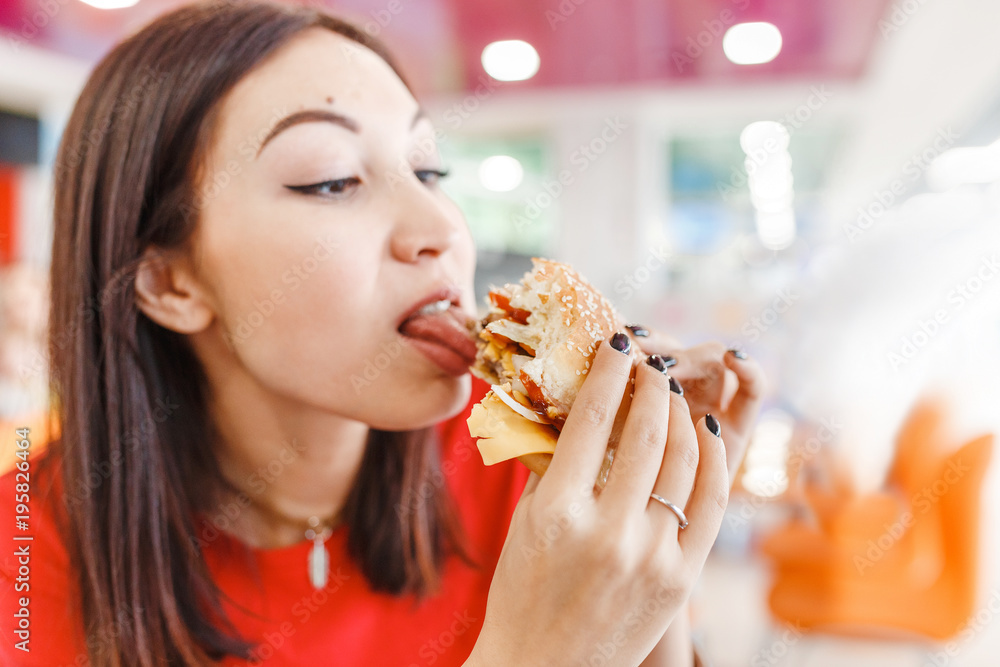 Healthy young woman biting her hamburger in fast food court Stock Photo ...