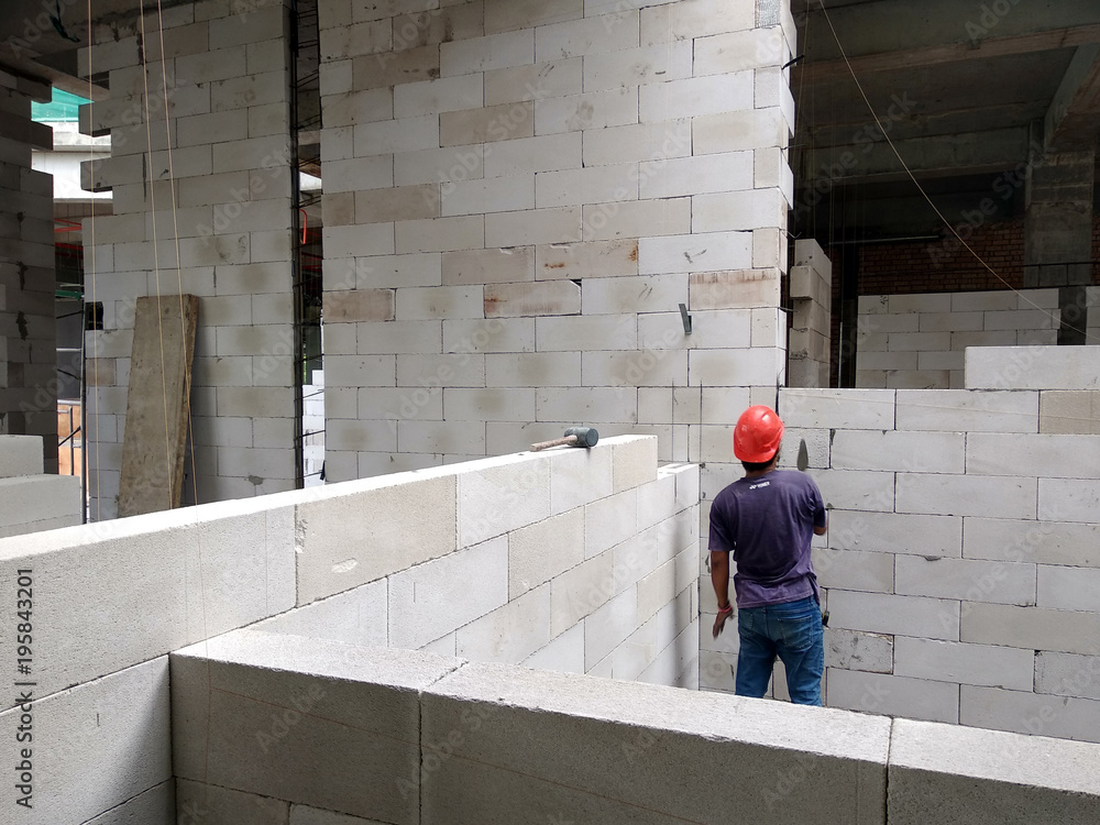 Construction workers installing lightweight block bricks to become wall ...