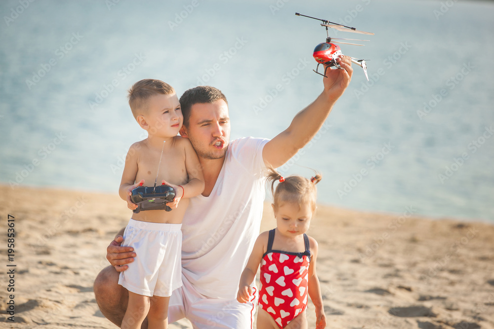 Young father teaching his kid to fly a helicopter outdoors. Young dad ...