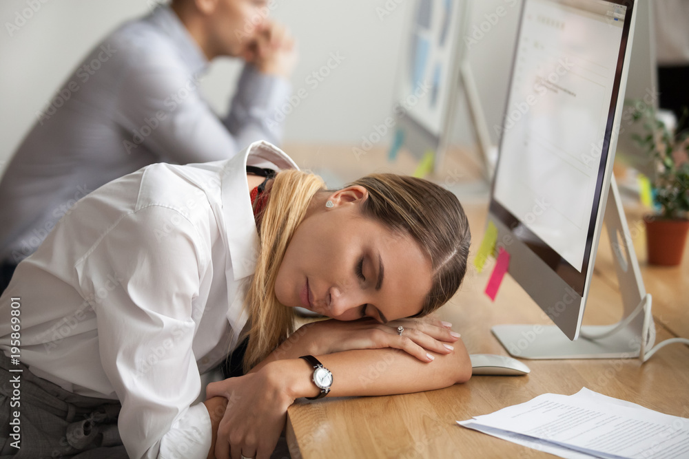 Exhausted young woman taking break to rest and having nap at workplace ...