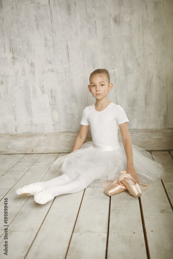 A little adorable young ballerina in white dress with point shoes ...