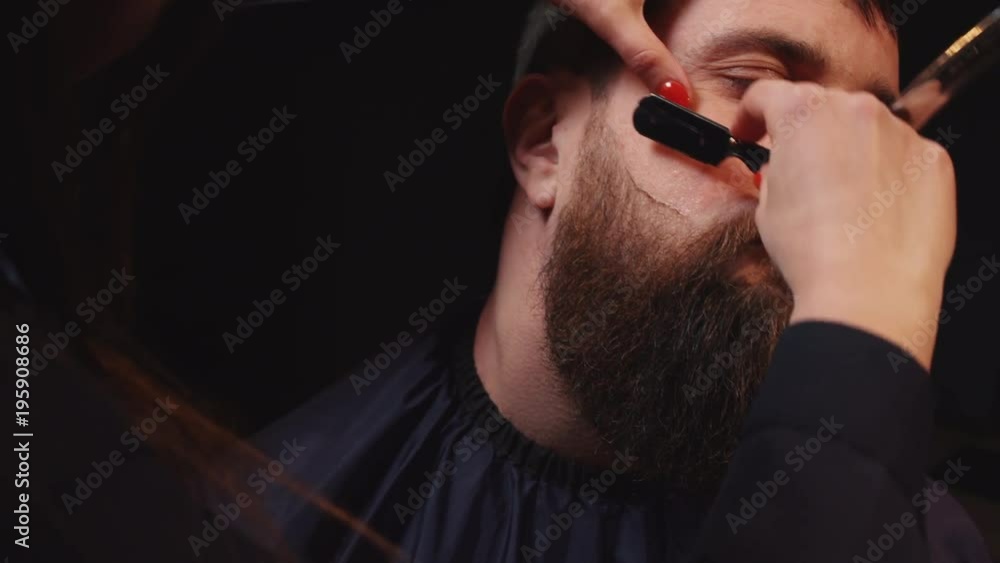 woman barber shaves customer with a dangerous razor in a barber, close ...