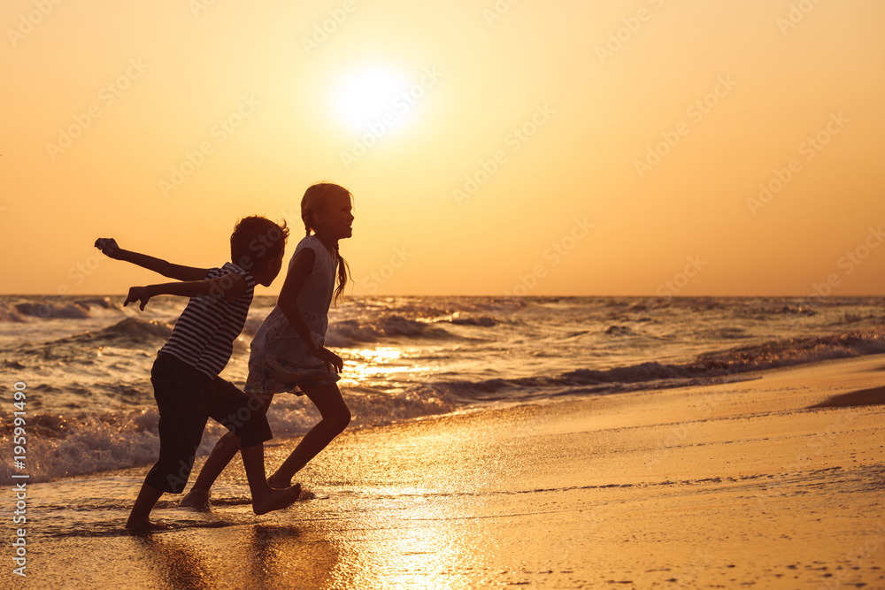 Happy children playing on the beach at the sunset time. Stock Photo ...