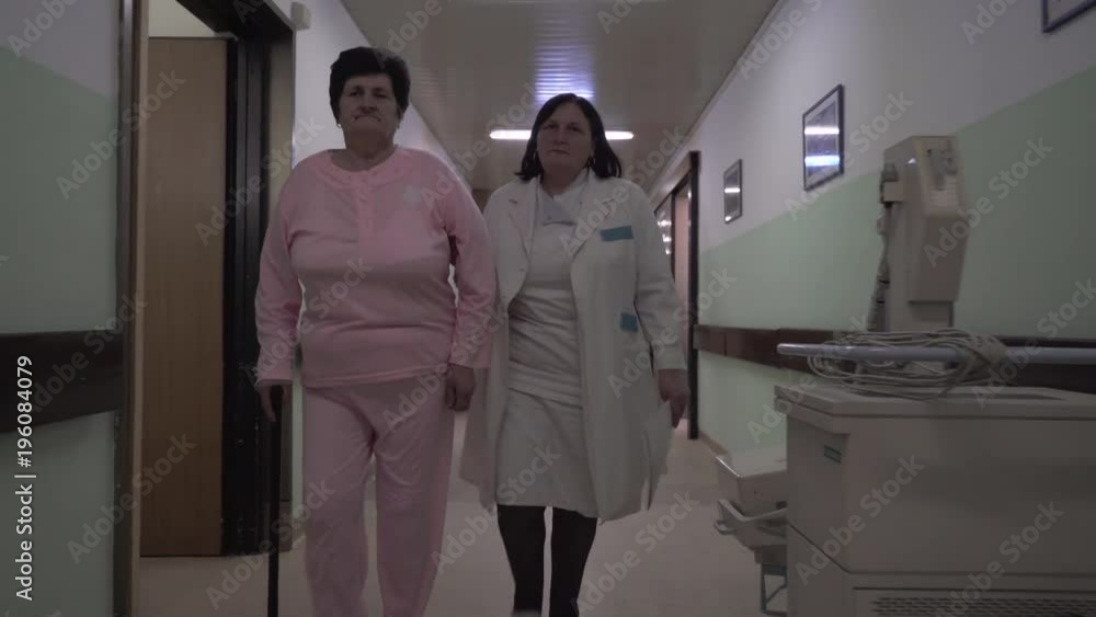 Nurse in purple uniform pushing trolley with medical tools and passing ...