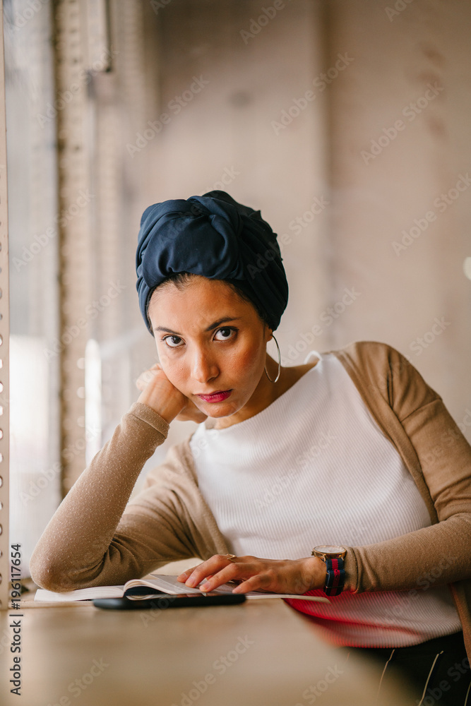 Young, attractive Muslim woman taking a break from reading a book. She ...